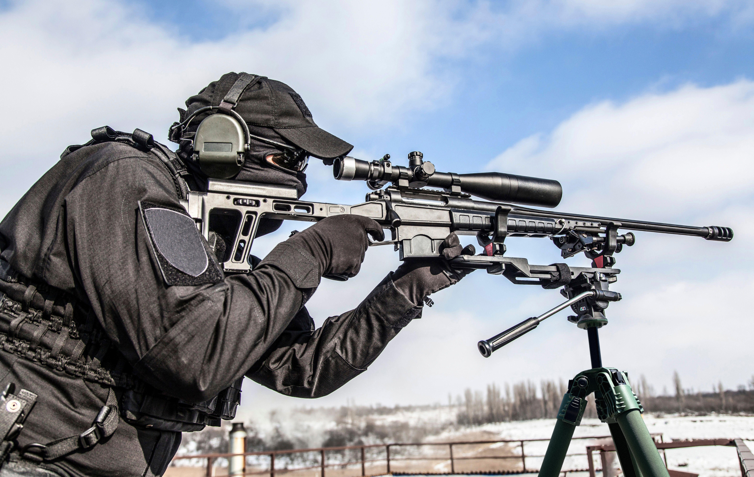 Sniper aiming with telescopic optical sight on sniper rifle mounted on ...